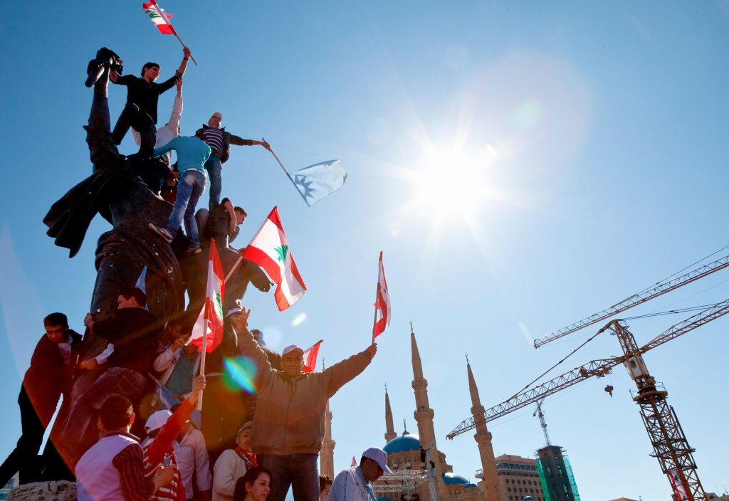 Political supporters with flags clamber over Martyrs Square monument in ...